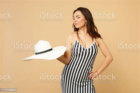 검은 색과 흰색 줄무늬 드레스 손에 들고 아름 다운 젊은 여자의 초상화 파스텔 베이 지 배경에 고립 된 모자를 찾고 사람들은 진심으로 감정 라이프 스타일 개념입니다 복사