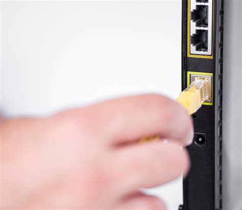 Mão conectando o cabo Ethernet ao roteador Foto Grátis