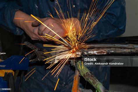 클로즈업 보기 강한 남자는 팔에 장갑 없이 파란색 작업 바지에 용접기 금속 제품은 차고 워크샵에서 용접 기계로 용접 파란색과