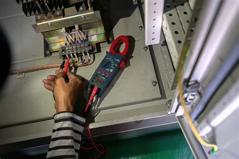전기 및 전기 유지 보수 서비스 엔지니어 손 회로 차단기 단자 및 케이블 배선 주 배전 보드에서 전류 전압을 확인하는 Ac 멀티 미터를 잡고 있습니다 전기 연료 및 전력