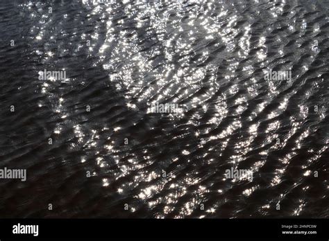 Detailed Close Up View On Water Surfaces With Waves And Ripples And The Sunlight Reflecting At