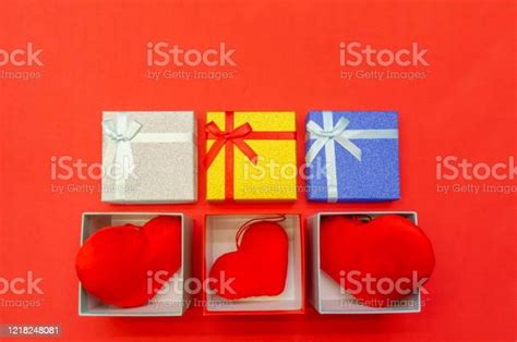 빨간색 배경 복사 공간에 빨간색 하트와 빨간 활빛나는 노란색 파란색 회색 선물 상자를 들고 상단보기 여성 손 각도에 대한 스톡