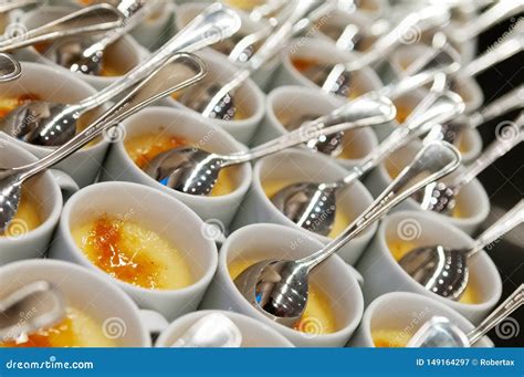 Creme Brulee In White Cups With Teaspoons Arranged On Table Stock Image