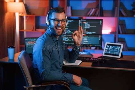 Positive Professional Programmer Is Working Indoors And Smiling Neon Lighting Stock Image