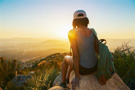 일몰을 보는 동안 바위 언덕 꼭대기에 앉아 여자 등산객의 후면 보기 아프리카계 미국 민족에 대한 스톡 사진 및 기타 이미지 아프리카계 미국 민족 하이킹 레저 활동