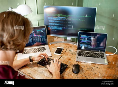 Young Programmer Writing A Program Code Sitting At The Workplace With