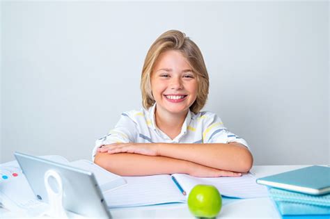 책상에 앉아 웃고 있는 중학교 소년 소녀는 교실에서 카메라를 보며 책과 태블릿을 공부하고 있다 빈 개념을 광고하기 위한 공간을 복사합니다 학교로 돌아 가기 어린 시절 교육