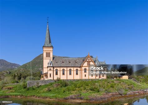 노르웨이 로포텐는 맑은 날을 우아하게 장식하며 유서 깊은 목조 건축물과 첨탑이 물에 반사되어 무성한 녹지와 험준한 언덕 사이에 자리 잡고 있습니다 0명에 대한 스톡 사진 및