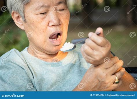 Asian Senior Woman Holding Spoon And Hands Tremor While Eating Rice