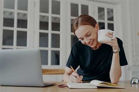 웃는 여자 글을 쓰고 노트북에 메모를 하고 하루 일정을 계획하고 노트북으로 책상에 앉아 35 39세에 대한 스톡 사진 및 기타 이미지 Istock