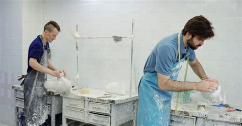 보철 공장의 두 젊은 남성 노동자가 작업장에서 절단단의 석고 캐스트를 연마하는 동안 테이블 옆에 서 있습니다 사진 Unsplash의 산업 이미지