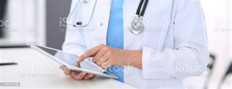 직장에서 알 수 없는 의사 여자 병원 또는 응급 병원에서 리셉션 데스크 근처에 서 있는 동안 디지털 태블릿을 사용 하 여 여성 의사 의학 및 의료 개념 건강 진단에 대한