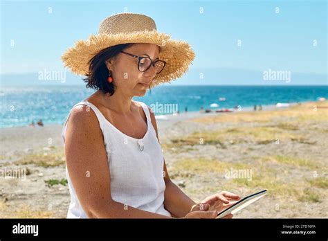 Femme Mature Portant Un Chapeau De Paille En Utilisant Une Tablette