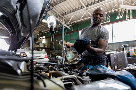 오일 품질을 확인하는 자동차 정비사 엔진 모터 자동차 변속기 및 유지 보수 장비 자동차 수리점의 자동차 정비사가 엔진을 점검하고
