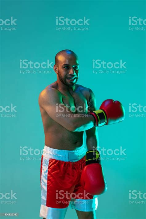 세로 이미지입니다 빨간 반바지와 장갑을 입은 프로 복서 한 명이 네온 라이트의 푸른 녹색 배경에서 포즈를 취하고 있습니다 25