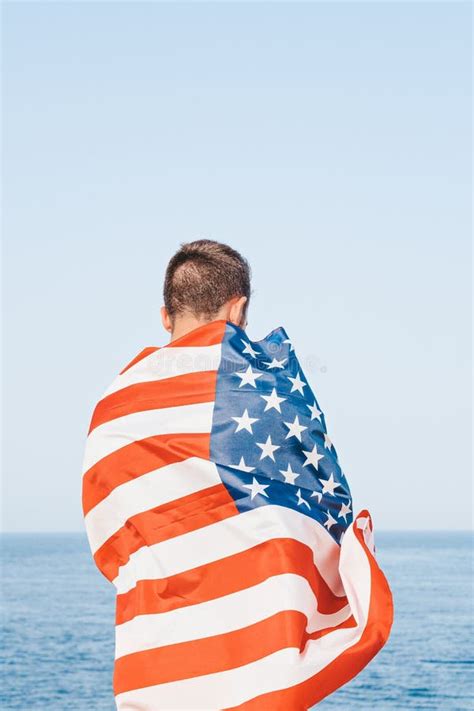 Man From Behind Wrapped In American Flag Against Blue Sky Stock Image Image Of Patriotism