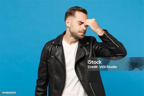 젊은 슬픈 좌절 까만 자 켓 흰색 T셔츠에 걱정 하지 않는 사람은 파란 벽 배경 스튜디오 초상화에 고립 된 머리에 팔을 넣어 사람들은 진심으로 감정 라이프 스타일 개념입니다