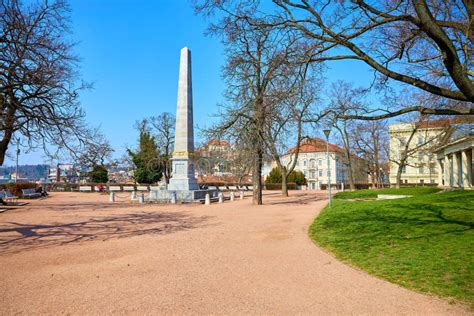 Historic Obelisk In European Urban Park With Bare Trees And Clear Sky