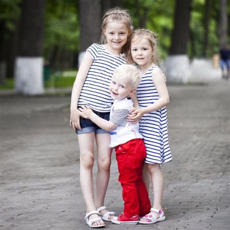 Little Boy And Two Older Cousins Meeting In The Summer Park Stock