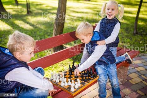 공원에서 벤치에서 여동생과 체스를 하는 어린 형제들 어린이 정보 개발 가족 여가 시간 야외 체스판에서 체스를 하는 아이들 소년 생각 열심히 에 체스 조합 3 명에 대한 스톡