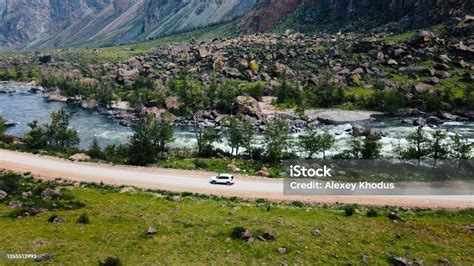 하얀 Suv 지프 차가 거대한 카투 야리크 협곡 슐리쉬만 계곡의 빈 시골 길을 따라 큰 산거품이 있는 강을 따라 운전하고 있다