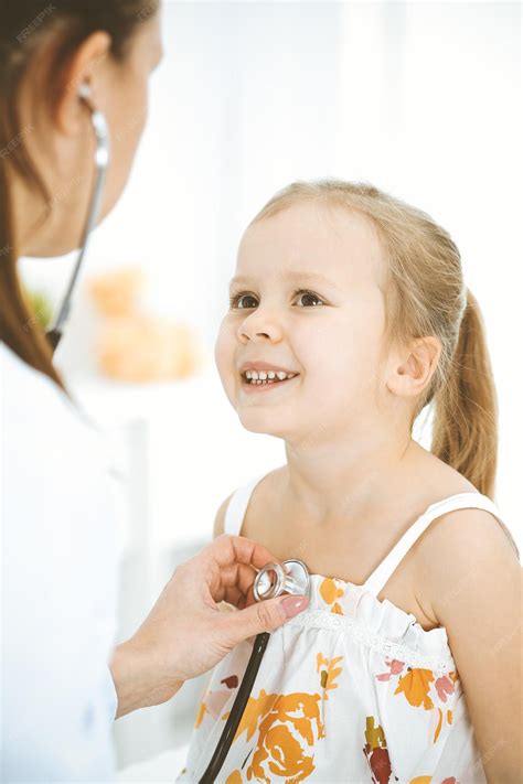 청진기로 어린 소녀를 검사하는 의사 일반적인 의료 검사에서 행복한 웃는 아이 환자 의학 및 건강 관리 개념입니다 프리미엄 사진