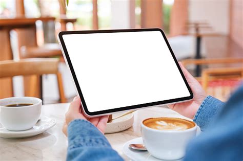 카페의 테이블에 케이크와 커피 컵이 있는 빈 흰색 데스크톱 화면이 있는 디지털 태블릿을 들고 있는 여성의 모형 이미지 35 39