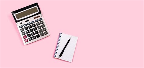 검은 펜과 흰 종이 공책이 있는 큰 은색 계산기가 분홍색 배경에 놓여 있습니다 금융 비즈니스 계산 교육 학교 수학 회계 컴퓨팅