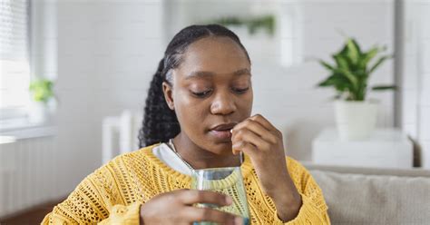 끔찍한 고통으로 고통받는 개념 아름다운 슬픔 화가 불행 문제 검은 머리를 가진 약한 여자 캐주얼 옷을 입고 소파에 앉아 약을 복용하고 있습니다 사진