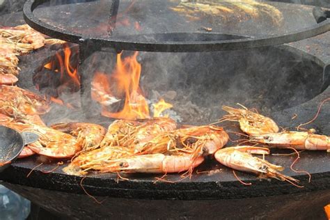 해산물 조각은 원뿔 모양의 그릇 모양으로 화덕 표면에서 조리됩니다 새우와 새우를 곁들인 그릇 모양의 납작한 그릴 야외 바베큐