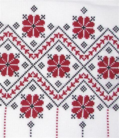 A Red And Black Cross Stitched Design On White Fabric With Flowers In