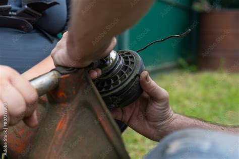 Replacing The Nylon Thread On A Grass Trimmer A Man Unscrews The Nut To Change The Line On The