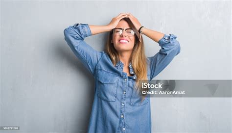 그런 지 회색 벽 때문에 두통 절망과 스트레스에서 고통 하는 안경 착용을 통해 젊은 성인 여자 통증과 편두통 머리에 손입니다 갈색 머리에 대한 스톡 사진 및 기타 이미지