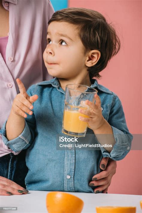신선한 오렌지 주스의 전체 유리를 들고 있는 귀여운 꼬마 소년과 식탁에 서 있는 동안 모자를 보면 2명에 대한 스톡 사진 및 기타 이미지 Istock