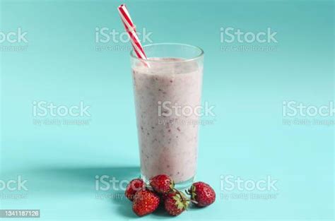 투명한 유리에 딸기와 빨간 빨대가 있는 밀크쉐이크가 파란색 배경을 클로즈업합니다 색을 입은 배경에 아이스크림 우유 열매의 칵테일 0명에 대한 스톡 사진 및 기타 이미지