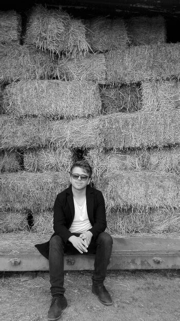 Premium Photo Portrait Of Man Sitting Against Hay Stack