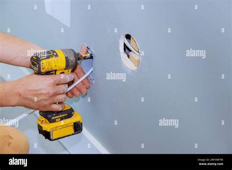 Professional Electrician Installing An Electric Socket In Wall Of