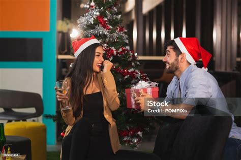 젊은 부부는 재미와 크리스마스 파티와 사랑에 백인 잘 생긴 남자는 아시아 여자 친구를 놀라게 선물 상자를 들고 새해 파티를 축하 12월에 대한 스톡 사진 및 기타 이미지