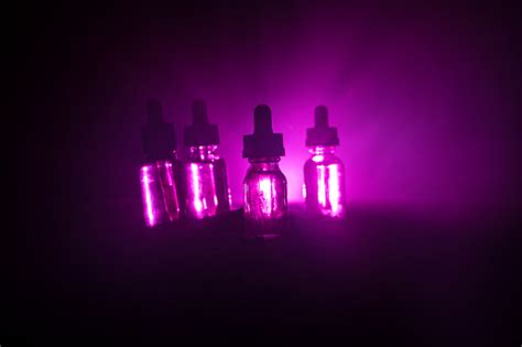 Vape 개념입니다 구름과 어두운 배경에 Vape 액체 병 연기 빛 효과입니다 배경 또는 Vape 광고 Vape 배경으로 유용 합니다 개념과 주제에 대한 스톡 사진 및 기타