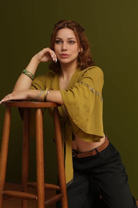 Free Fashionable Woman In Earth Toned Outfit Posing Against Green