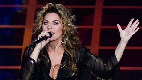 A Woman Singing Into A Microphone While Holding Her Hand Up In The Air