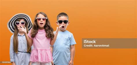 오렌지 배경 위에 소년과 소녀 아이 들의 그룹은 깜짝 얼굴로 충격에 무서 워 두려워 하 고 공포 표현으로 흥분 감정에 대한 스톡