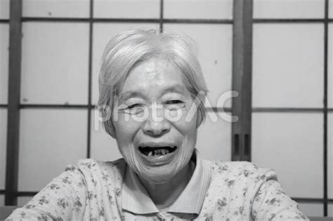 障子窓の前に座ってボロシャツを着た笑顔の幸せそうなおばあちゃん No 4906580｜写真素材なら「写真ac」無料（フリー）ダウンロードok