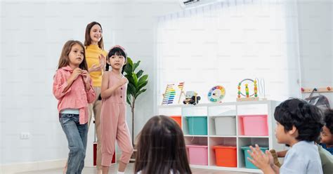 아시아의 아름다운 젊은 여성 교사가 학교에서 아이에게 수업을 가르치고 있다 매력적인 여성 강사 마스터가 유치원 교실에서 재미있는 활동으로 어린이 학생을 설명하고 교육합니다
