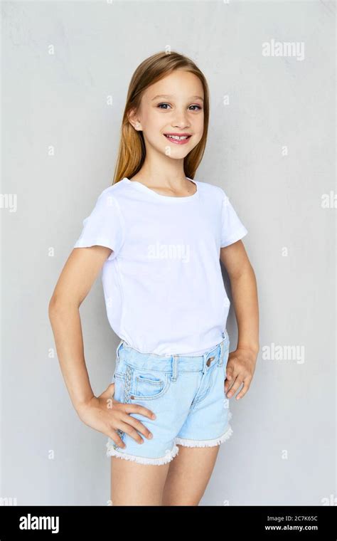 Young Sportive Girl In White T Shirt And Jeans Shorts Posing In Studio