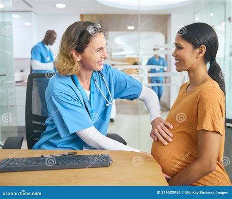 Female Nurse Or Doctor Wearing Scrubs Examining Pregnant Woman In