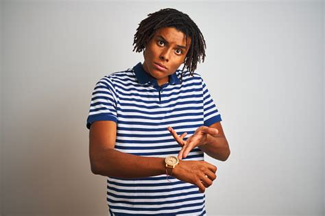 고립 된 흰색 배경 위에 서있는 줄무늬 파란색 폴로를 입은 공포를 가진 아프로 남자 시간 조바심 화가 및 마감 지연에 대한 화가 를 가리키는 서둘러 가리키기에 대한 스톡