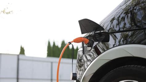 Woman Connects An Electric Car To The Charger And Adjusts The Process Of Charging The Car