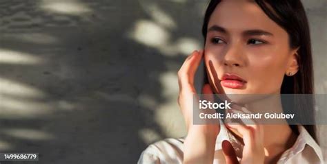 흰 셔츠를 입은 젊은 아가씨의 초상화는 나뭇잎 그늘에서 포즈를 취하고 사려 깊은 시선을 돌린다 긍정적인 사랑스러운 여자는 질감이