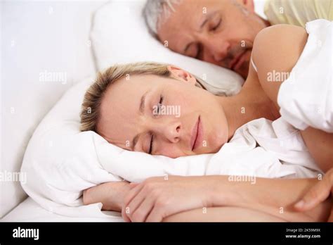 Cuddling Couple Closeup Of A Mature Couple Embracing While Sleeping Peacefully Next To Each